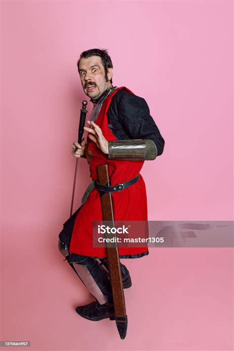 무서운 남자 중세 전사 또는 갑옷 옷을 입은 기사의 전체 길이 초상화 분홍색 스튜디오 배경에 고립 된 빨간 의상 재미있는 밈 감정 르네상스에 대한 스톡 사진 및 기타 이미지