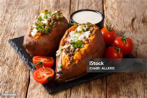 렌틸콩 마늘 파슬리로 속을 채운 소박한 스타일의 구운 고구마는 슬레이트 보드에 사워 크림 클로즈업과 함께 제공됩니다 수평 0명에 대한 스톡 사진 및 기타 이미지 Istock