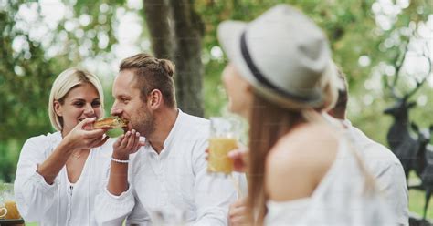 여자는 낮에 친구들과 야외에서 맛있는 샌드위치를 남편에게 먹인다 사진 Unsplash의 피크닉 이미지