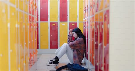 슬픈 십대 학생이 화려한 사물함 근처의 복도에 앉아 캠퍼스 복도에서 배낭을 메고 학교 개념으로 돌아가는 책을 포장합니다 사진 Unsplash의 청년기 이미지