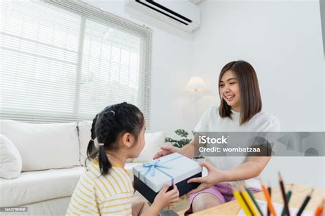 엄마에게 어머니의 날 선물을 주는 파란 선물 상자를 들고 있는 고마운 아시아 소녀 행복한 엄마와 귀여운 딸 아이가 생일을