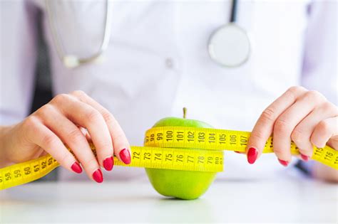 다이어트입니다 피트 니스 및 건강 식품 다이어트 개념 야채와 함께 균형 잡힌 다이어트입니다 그녀의 사무실에서 녹색 사과 측정 하는 쾌활 한 의사 영양사의 초상화 자연 식품과