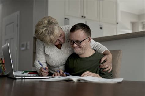 Hugging Caucasian Man With Down Syndrome While Learning At Home Stock