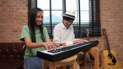 Young Asian Girl Is Learning How To Play Keyboard From Teacher In After Young Asian Girl Is Learning How To Play Keyboard From Teacher In After