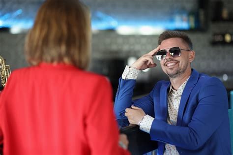 수염과 선글라스를 착용한 파란색 재킷을 입은 행복한 남자가 머리를 손에 들고 바에 앉아 있다 2명에 대한 스톡 사진 및 기타 이미지 Istock