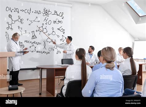 Professors Giving Lecture In Chemistry To Audience In Conference Room Projection Screen With