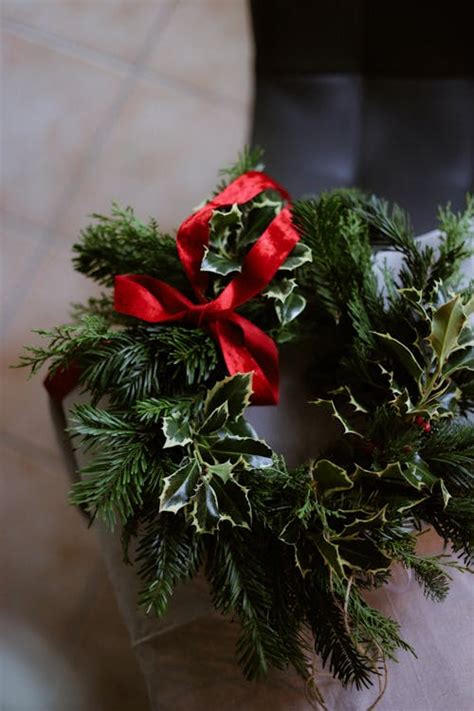 Святковий різдвяний вінок з Холлі та червоною стрічкою · Безкоштовне стокове фото