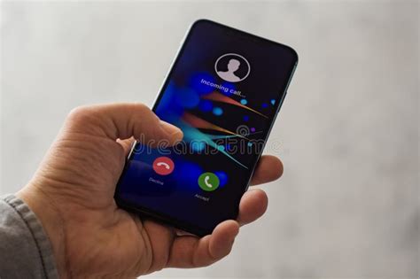 Close Up Of A Hand Holding A Smartphone With An Incoming Call Screen Display Shows Incoming