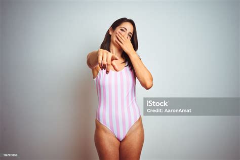 젊은 아름다운 여자 를 입고 줄무늬 핑크 수영복 수영복 위에 고립 된 배경 웃음 입에 손으로 카메라에 손가락을 가리키는 수치 표정 가리키기에 대한 스톡 사진 및 기타 이미지