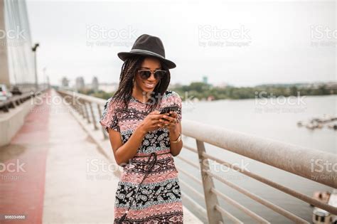 그녀의 머리에 모자와 젊은 아프리카계 미국인 여자는 문자 메시지와 그녀의 스마트폰 강에 대한 스톡 사진 및 기타 이미지 강 낮 도시 Istock