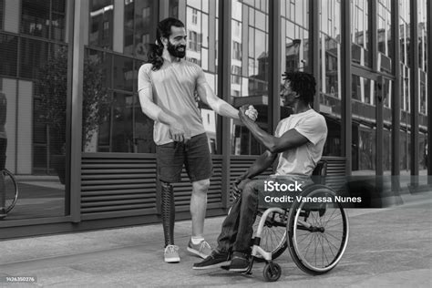 신체 장애를 가진 다인종 사람들이 야외에서 서로 인사 나누다 휠체어에 앉아있는 아프리카 남자에 집중 흑백 편집 2명에 대한 스톡 사진 및 기타 이미지 Istock