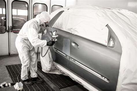 페인팅 부스의 자동차 부품에 페인트 코트를 적용 한 전체 작업복과 호흡 마스크의 차체 공장 기술자 그림 그리기에 대한 스톡 사진