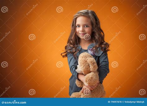 Милая жизнерадостная маленькая девочка на оранжевой предпосылке Стоковое Фото изображение