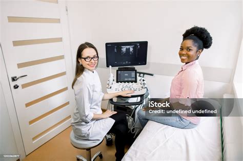 소파에 앉아 초음파 검사실에서 의사와 이야기하는 젊은 행복한 미소 아프리카 여성 초음파 검사 후 의사와 환자 말하고 카메라를보고