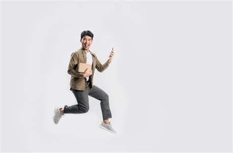 전체 길이 잘 생긴 아시아 남자 들고 상자와 스마트 폰을 사용하여 그는 흰색 배경에 공중에서 점프하고 있습니다 남자에 대한 스톡 사진 및 기타 이미지 Istock
