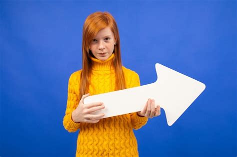 Premium Photo Red Haired Girl Holds The Right Arrow Pointer On Blue