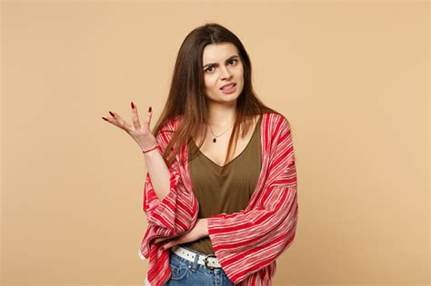 캐주얼 한 옷 카메라를 찾고에 자극 젊은 여자의 초상화 스튜디오에서 파스텔 베이 지 벽 배경에 고립 된 손을 확산 사람들은 진심으로 감정 라이프 스타일 개념입니다 복사