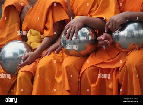 Buddhist Monks Wearing Orange Robes Sit With Their Alms Bowls Near Tha