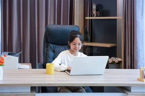 Young Asian Schoolgirl Is Doing Her Class Homework Assignment At Home Using Laptop Computer For