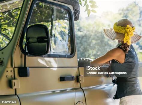 밀짚 모자를 쓴 여자는 긴 여행 후 오프로드 차에 기대어 있습니다 컨셉 카는 자연을 통과합니다 4x4 자동차에 대한 스톡 사진