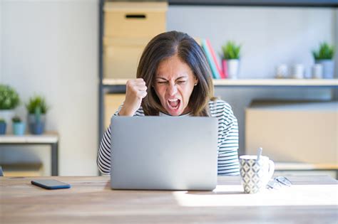 집에서 일하는 중년 노인 여성은 컴퓨터 노트북을 사용하여 일하고 화가 나서 분노를 외치면서 좌절하고 분노했습니다 분노와 공격적인 개념 갈색 머리에 대한 스톡 사진 및 기타