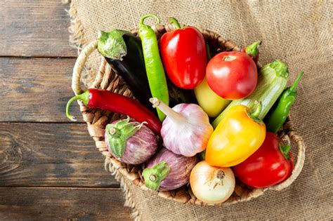 갈색 나무 테이블에 바구니에 신선한 야채 바구니에 생 야채를 많이 테이블에 가지 토마토 마늘 달콤한 고추 양파 텍스트 공간이 있는 위쪽 보기입니다 건강 식품 가을에 대한