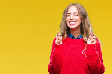 아름 다운 젊은 금발 여자 횡단 손가락 희망 및 눈을 감고 미소 격리 된 배경 위에 겨울 스웨터를 입고 행운과 미신의 개념입니다 겨울에 대한 스톡 사진 및 기타 이미지