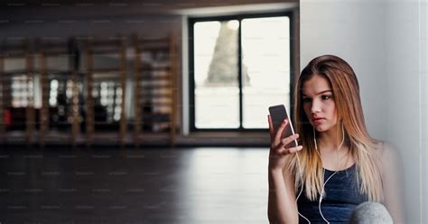 체육관에서 이어폰과 스마트폰을 들고 음악을 듣고 있는 어린 소녀 또는 여성 사진 Unsplash의 사진술 이미지