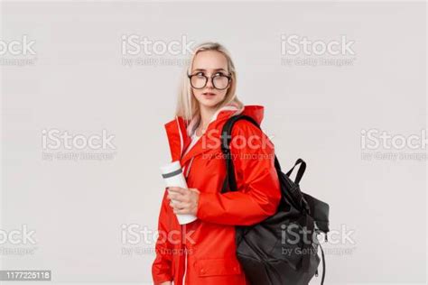 추운 계절에 검은 색 배낭과 흰색 열 머그잔으로 여행 빨간색 비옷과 안경에 금발 소녀 우기 비옷에 대한 스톡 사진 및 기타