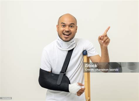 충격을 받은 얼굴 남자가 팔과 다리가 부러져 빈 공간을 가리키고 있다 남자는 지팡이 목발로 석고 캐스트 부목을 착용했습니다 목 칼라가 있는 슬링 지지 팔을 착용한 환자 생명