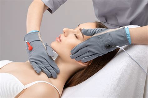 미용사 의사는 미용실에서 젊은 아름다운 소녀의 얼굴과 목에 미세 전류 마사지 절차를 만듭니다 보호 장갑에 대한 스톡 사진 및 기타 이미지 Istock