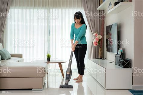 캐주얼 한 옷을 입고 아시아 젊은 여성은 일상 적인 가사 루틴에 대 한 자유 시간을 사용 하 여 집에서 진공 청소기를 사용 하