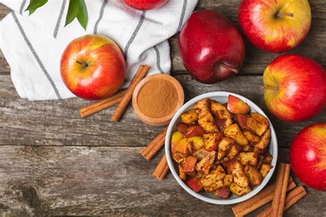 질감이 있는 나무 배경에 계피를 곁들인 사과 향긋한 빨간 양념 사과와 계피 스틱 스타 아니스 매운 향신료를 곁들인 사과 조각 텍스트의 위치 공간을 복사합니다 수확 과일 0