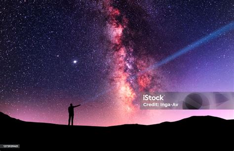 밝은 은하와 아름다운 별이 빛나는 하늘 야간 풍경 손전등이 별이 빛나는 하늘을 비추는 사람 실루엣이 해안가에 서 있습니다 밤