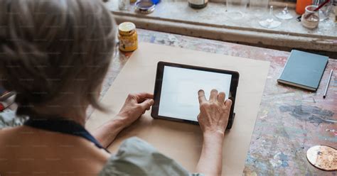 테이블에 앉아 원격 수업을 준비하는 동안 태블릿 화면에 타이핑하는 노인 여성의 높은 각도 보기 사람과 기술 개념 사진 Unsplash의 먼 이미지