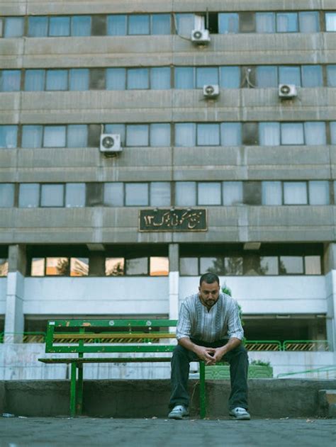 건물 밖 벤치에 앉아 있는 명상하는 남자 · 무료 스톡 사진