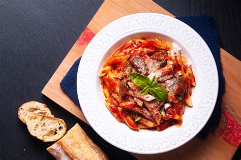 음식 개념 수제 유기농 시칠리아 파스타 알라 노마 펜과 복사 공간이있는 검은 배경에 나무 보드에 가지 토마토 소스를 곁들입니다 파스타에 대한 스톡 사진 및 기타 이미지