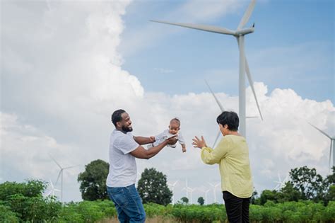 한 남자와 한 여자가 풍차를 배경으로 들판에서 아기와 놀고 있습니다 전기 엔지니어 환경 에너지 깨끗한 지속 가능 풍력 터빈 자연 2 5 개월에 대한 스톡 사진 및 기타