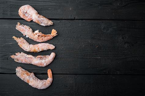 검은 색 나무 테이블 배경에 머리와 냉동 야생 아르헨티나 붉은 새우 상단 보기 평면 누워 카피 스페이스와 텍스트 공간을 가진 0