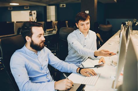 노트북에서 Office 프로젝트에서 작업 하는 동안 그래픽 태블릿와 동료에 대 한 컴퓨터 모니터에서 가리키는 젊은 남자 디자인