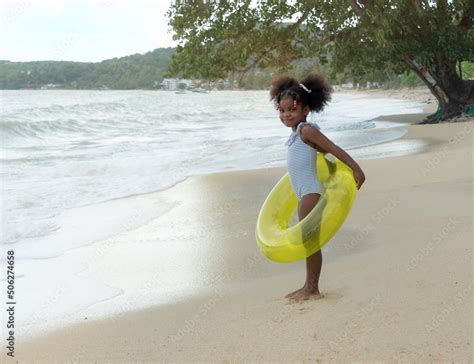 Cute Little African Girl In Striped Swimsuit With Yellow Inflatable