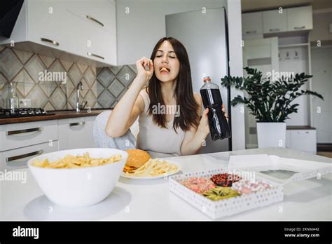 A Woman Eats Junk Food At Home In The Kitchen Stock Photo Alamy