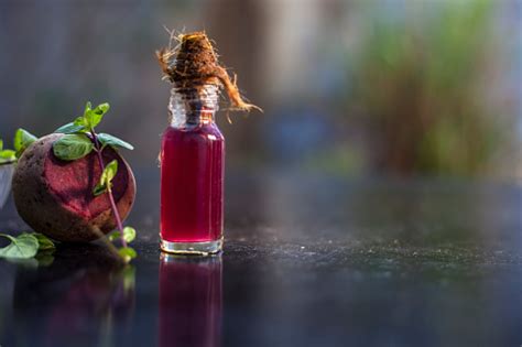 신선한 생 슬라이스 비트 뿌리와 민트 잎 추출된 해독 에센셜 오일을 작은 유리 병에 담습니다 흐린 배경이 있는 수평 촬영 가볍게