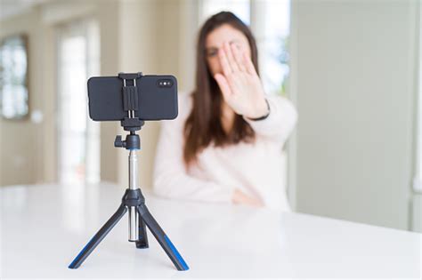 심각하고 자신감있는 표정 방어 제스처와 정지 기호를하고 열린 손으로 스마트 폰 웹캠과 셀카 비디오를 녹화 아름다운 젊은 여자