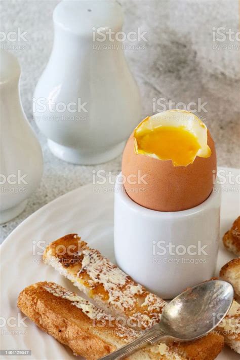군인 콧물 노른자 버터를 곁들인 흰 빵 토스트 조각 흰 달걀 컵 금속 티스푼 소금 통 대리석 효과 배경 전경에 초점 0명에 대한