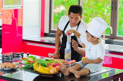 개인 태국 요리사 요리 현대적인 스타일의 집 부엌 테이블에 앉아 인근 요리사의 모자에 그의 작은 아들 태국 음식 만들기 혼합 야채 굴 소스 2 3 살에 대한 스톡 사진 및