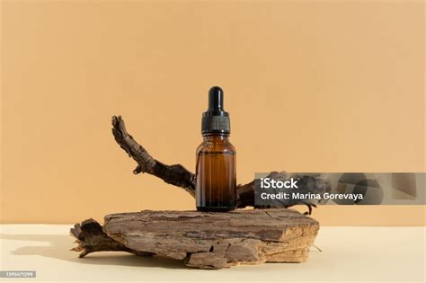 히알루 론산이 든 진한 호박색 유리 병 또는 베이지 색 배경의 마른 가지 근처의 얼굴 혈청 유기 성분을 가진 개념 천연 화장품 디자인의 공간을 복사합니다 정면보기