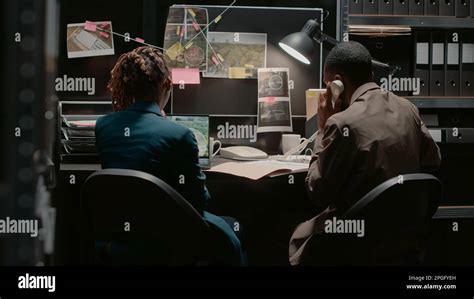 Private Investigators Examining Surveillance Photos And Reading Case File In Police Agency