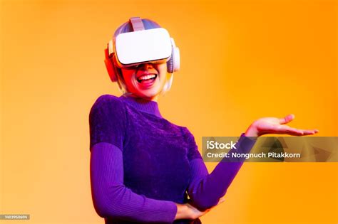 메타버스 콘셉트 보라색 셔츠 사이버펑크 헤어 스타일을 입은 젊은 아시아 여성 화이트 Vr 헤드셋 착용 주황색 스크린 배경에서 터치를 감상하는 연주 Brand Name