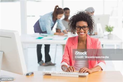 사무실에서 배경에 동료와 컴퓨터를 사용 하는 여성 예술가 사무실에 대한 스톡 사진 및 기타 이미지 사무실 컴퓨터 타자 치기 Istock
